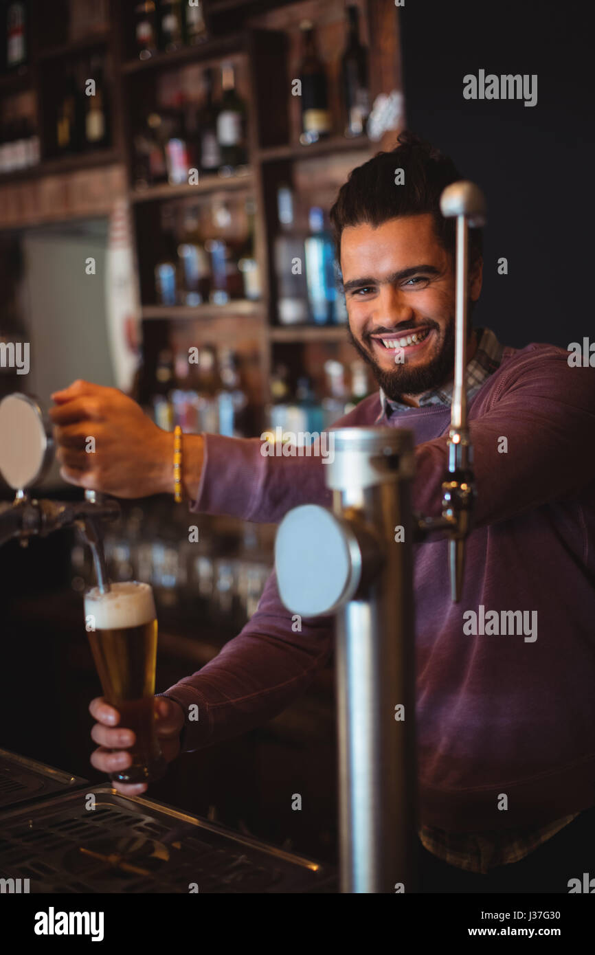 Bar tender filling beer from bar pump at bar counter Stock Photo - Alamy