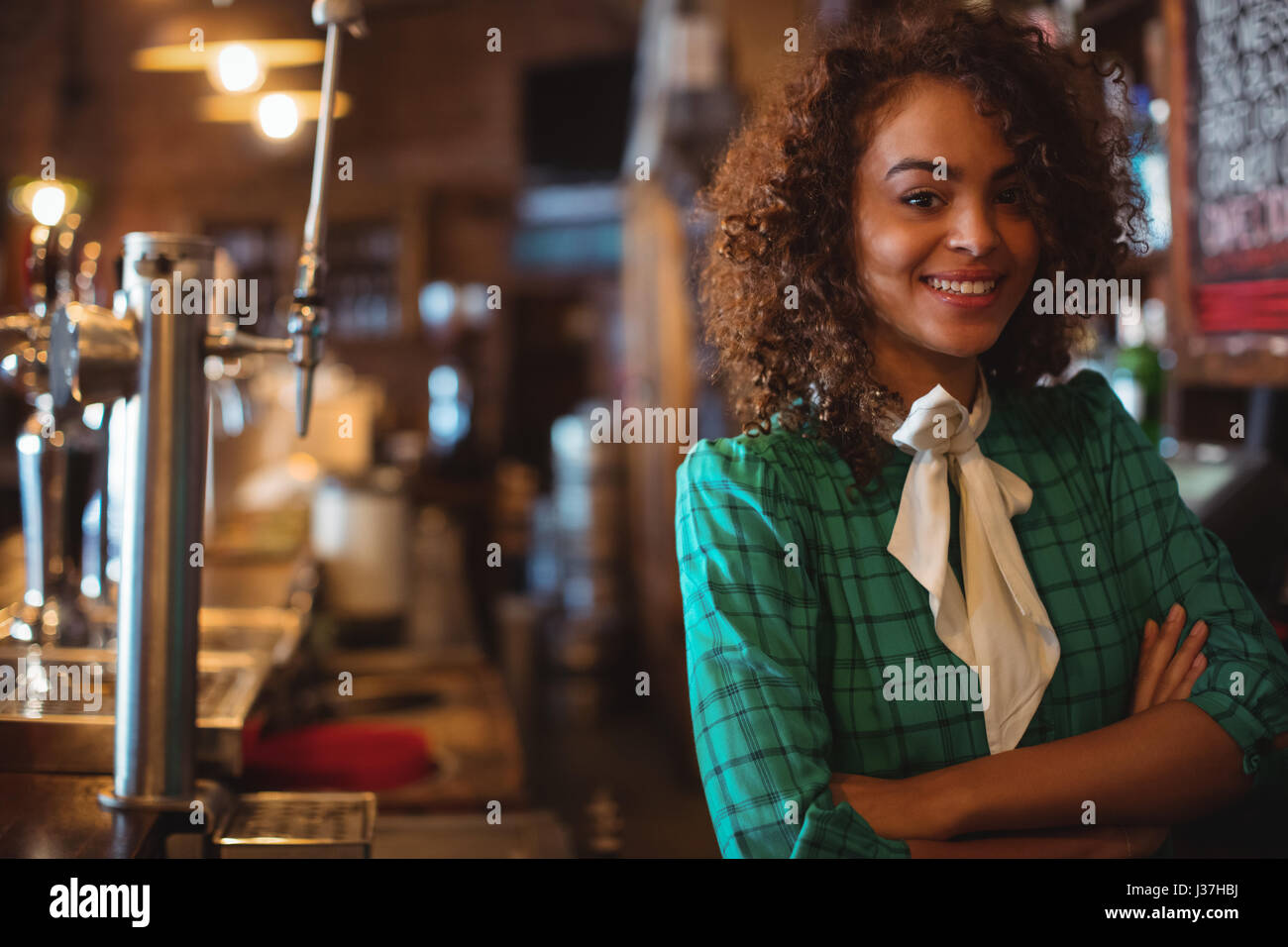 Portrait of waitress standing with arms crossed at counter in pub Stock ...