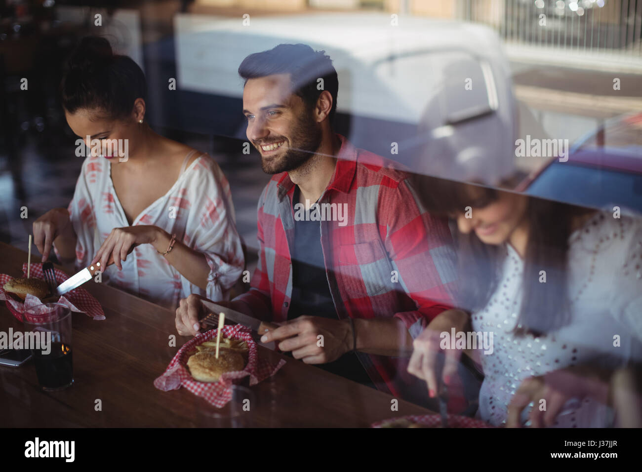 Friends having burger together at restaurant Stock Photo - Alamy