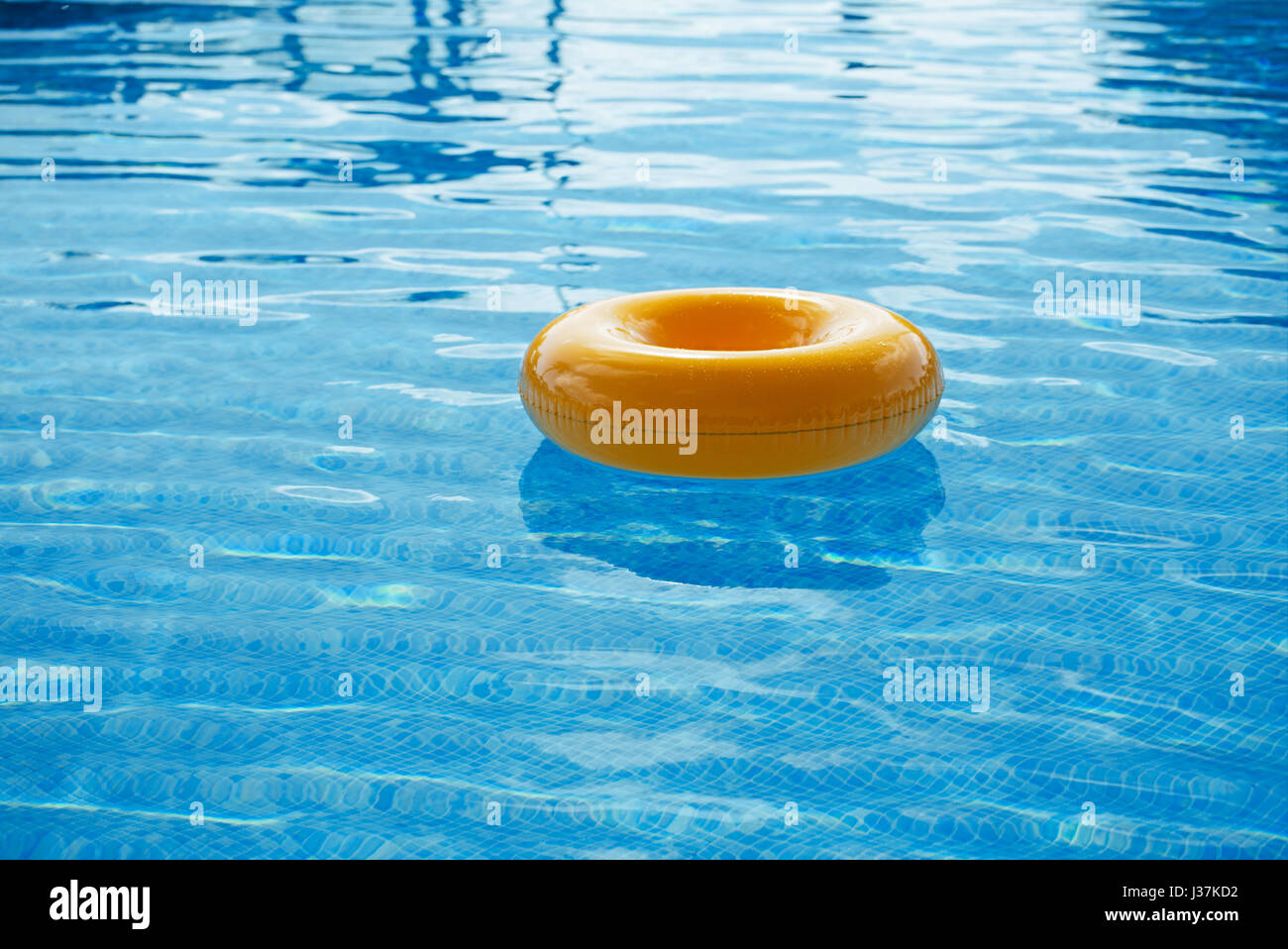 floating ring on blue water swimpool with waves reflecting in the ...