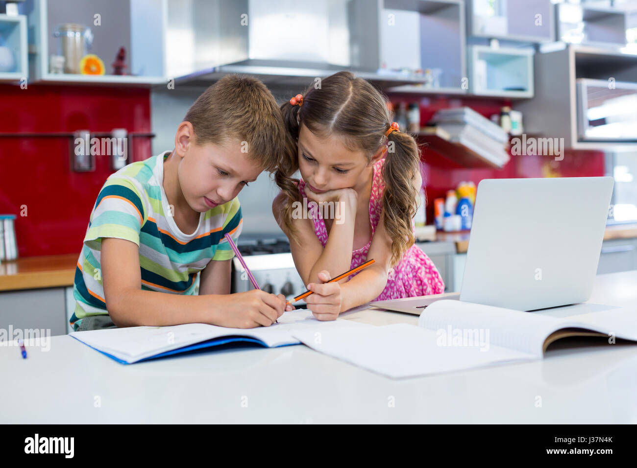 Siblings doing homework in kitchen at home Stock Photo - Alamy