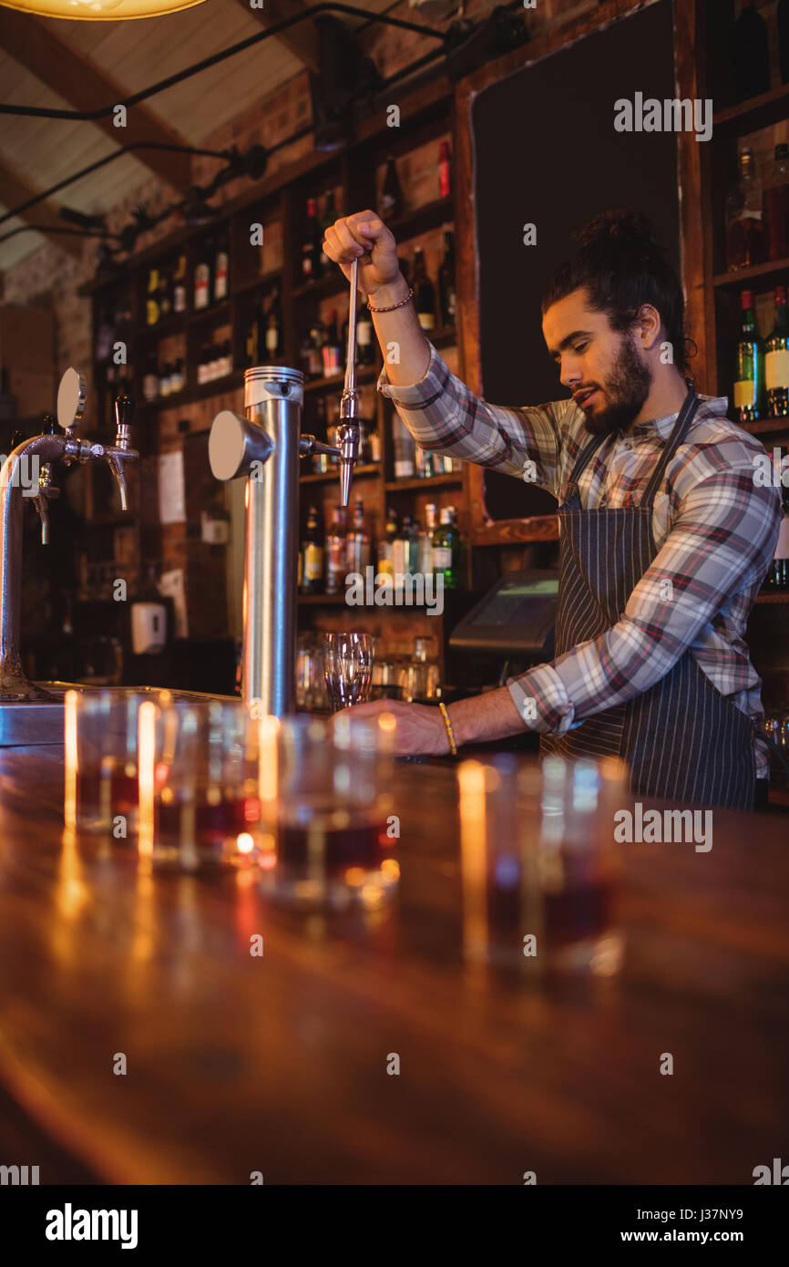 Waiter using beer tap at counter in pub Stock Photo - Alamy