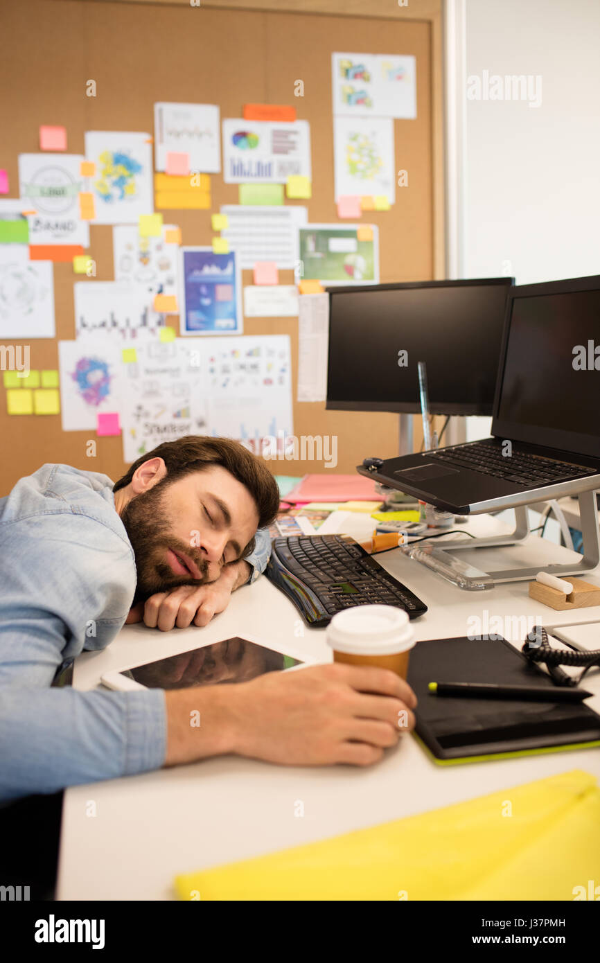 Tired businessman napping on desk in creative office Stock Photo - Alamy
