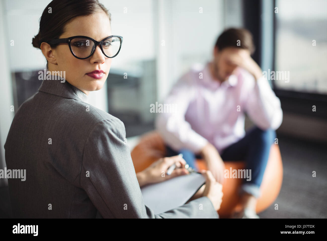Portrait of counselor with man in background during therapy Stock Photo ...