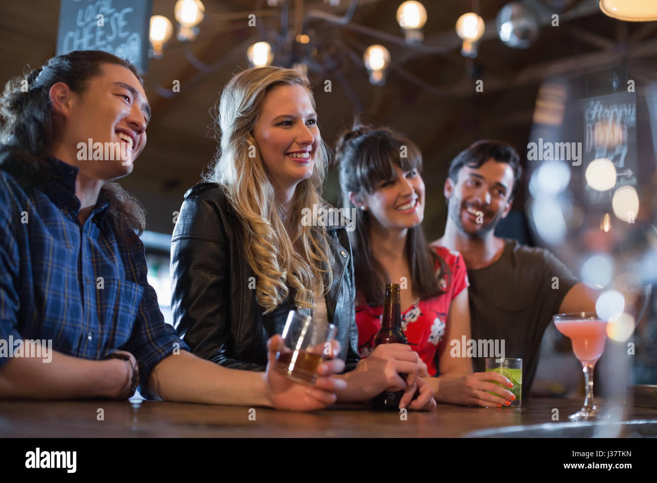 Smiling friends counter looking away at bar in pub Stock Photo - Alamy