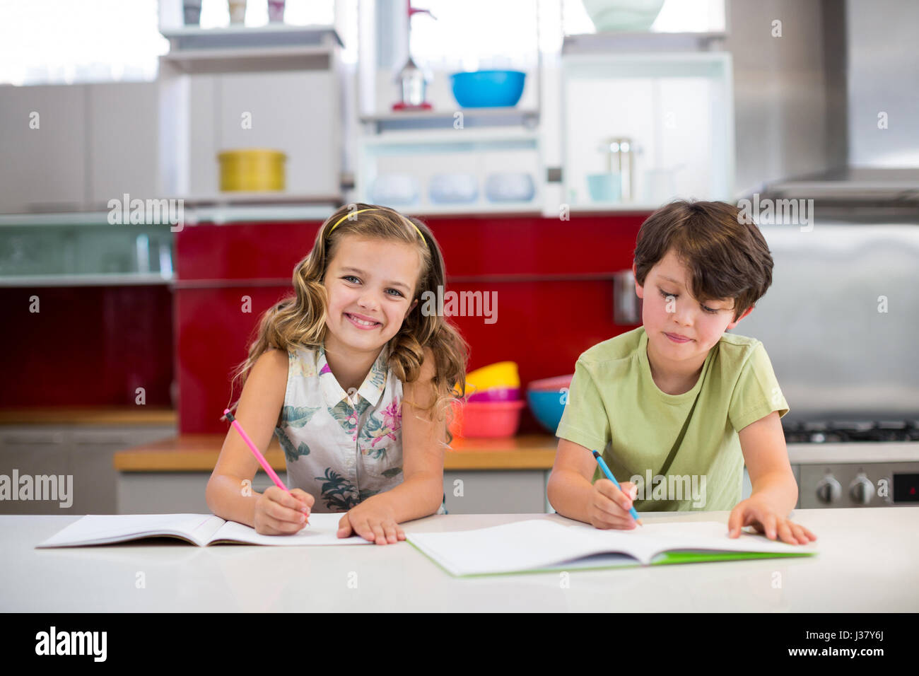 Siblings doing homework in kitchen at home Stock Photo - Alamy