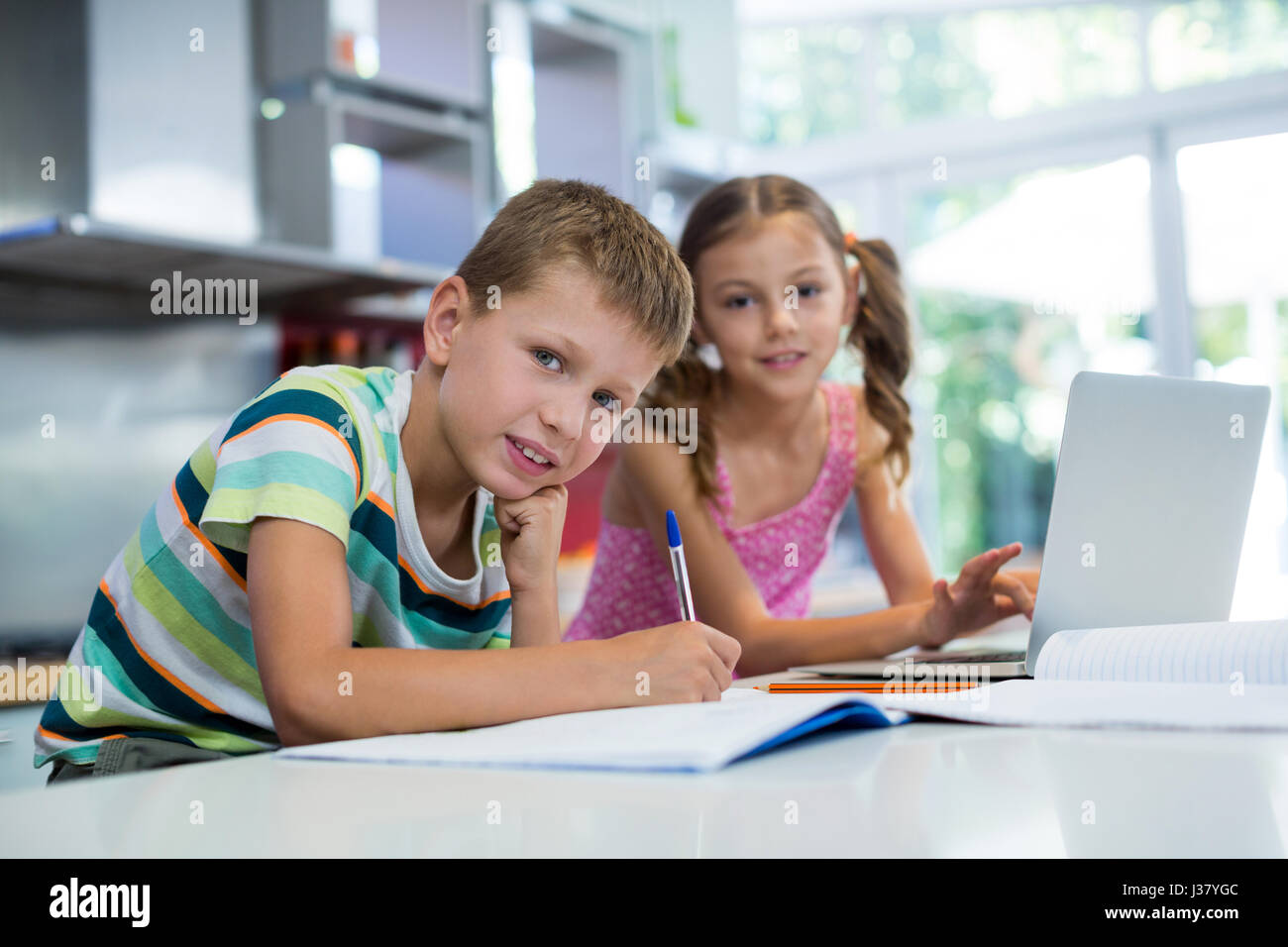 Portrait of siblings doing their homework in kitchen at home Stock ...
