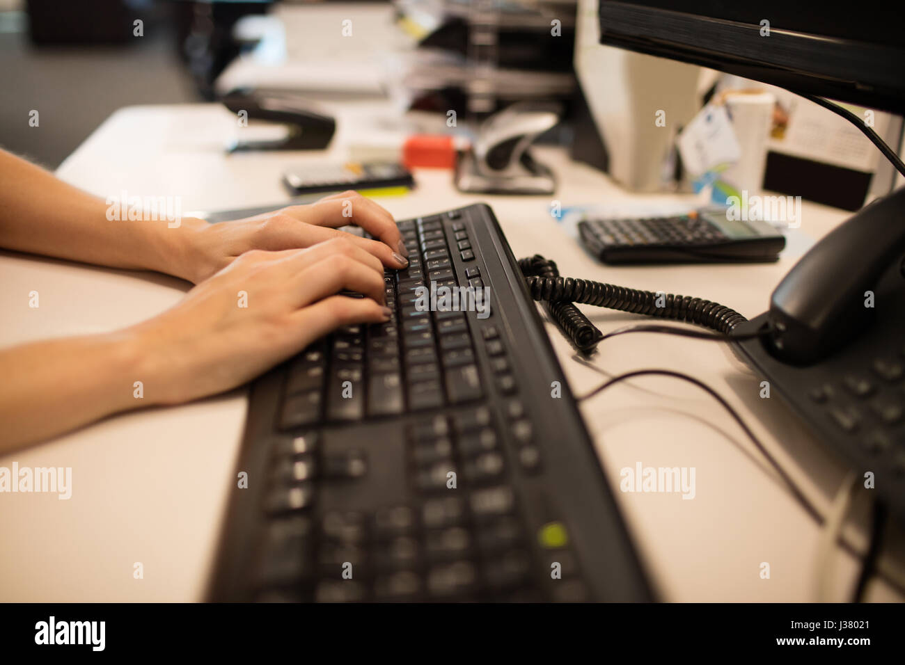 Cropped hands of businesswoman using computer keyboard on desk at ...