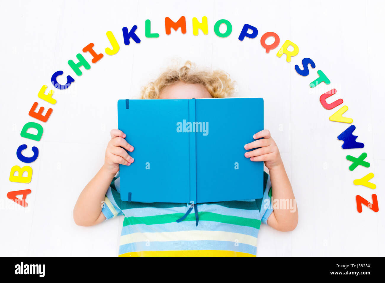 Happy preschool child learning to read and write playing with colorful ...