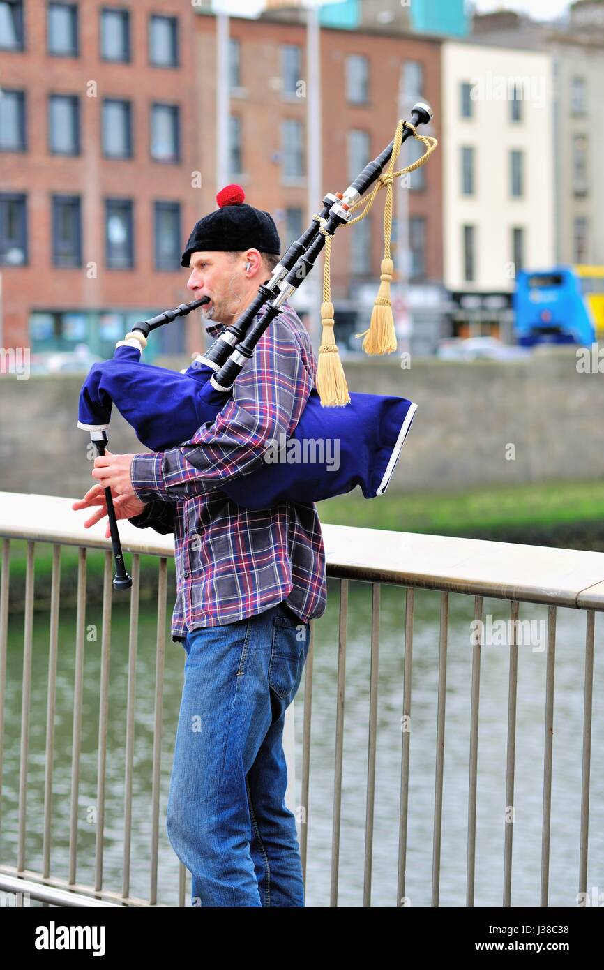 An Irish piper playing the bag pipes on the Ha'penny Bridge over the ...