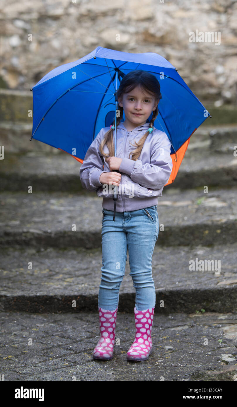 Little girl playing in the rain under umbrella Stock Photo - Alamy