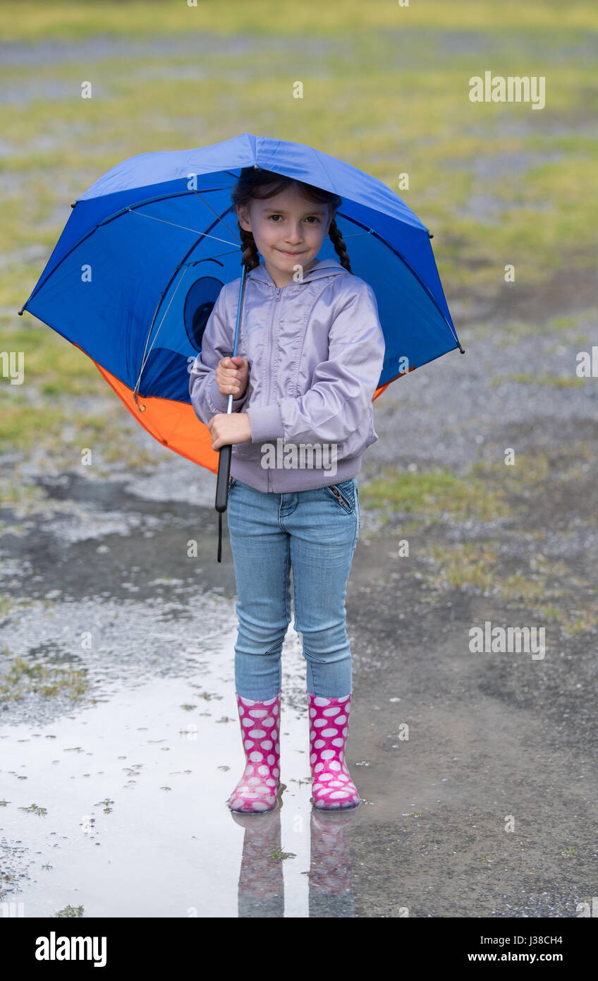 Little girl playing in the rain under umbrella Stock Photo - Alamy