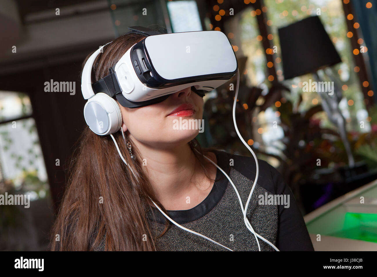 Young woman wearing virtual reality device in the headphones, watching ...
