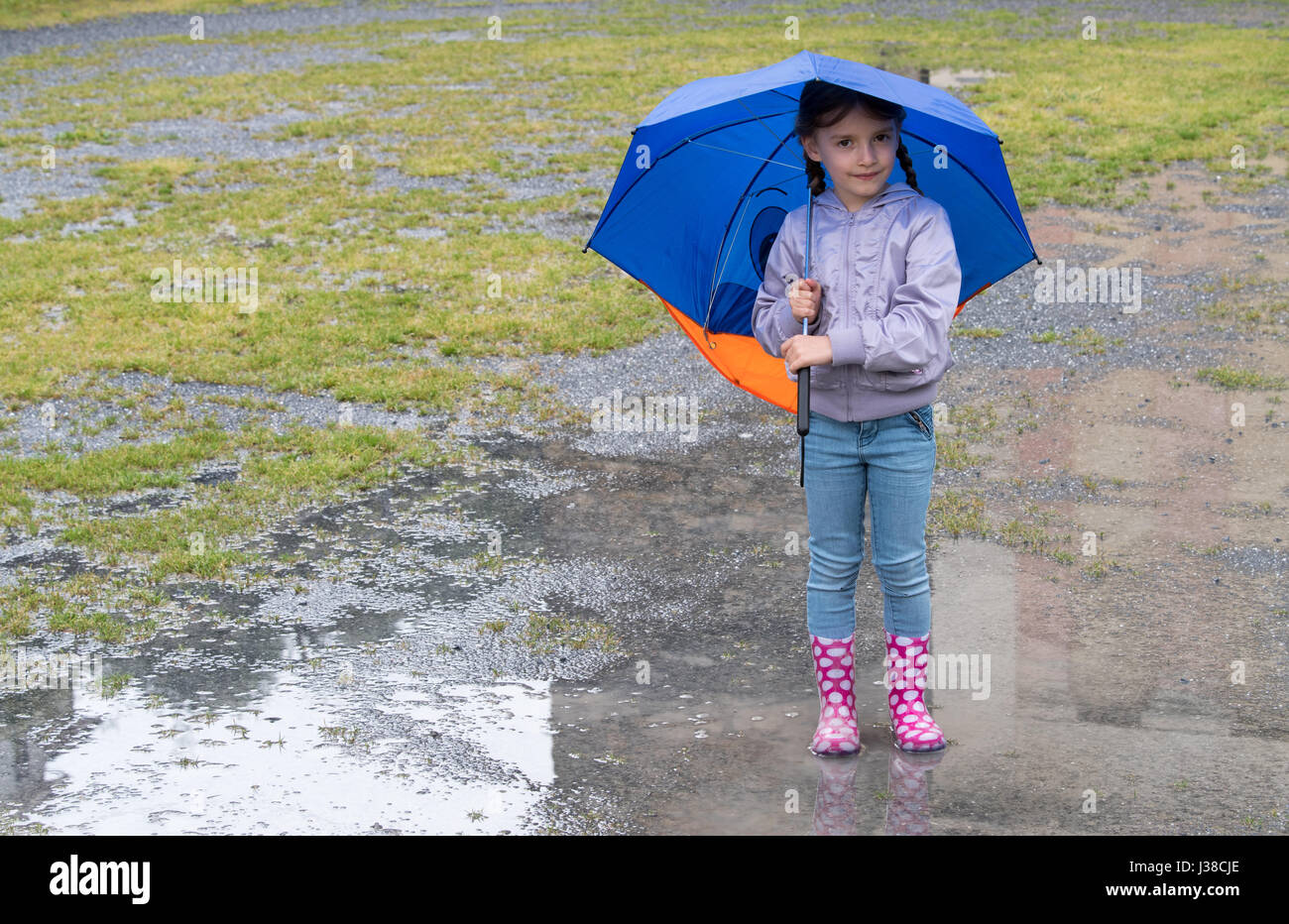 Little girl playing in the rain under umbrella Stock Photo - Alamy