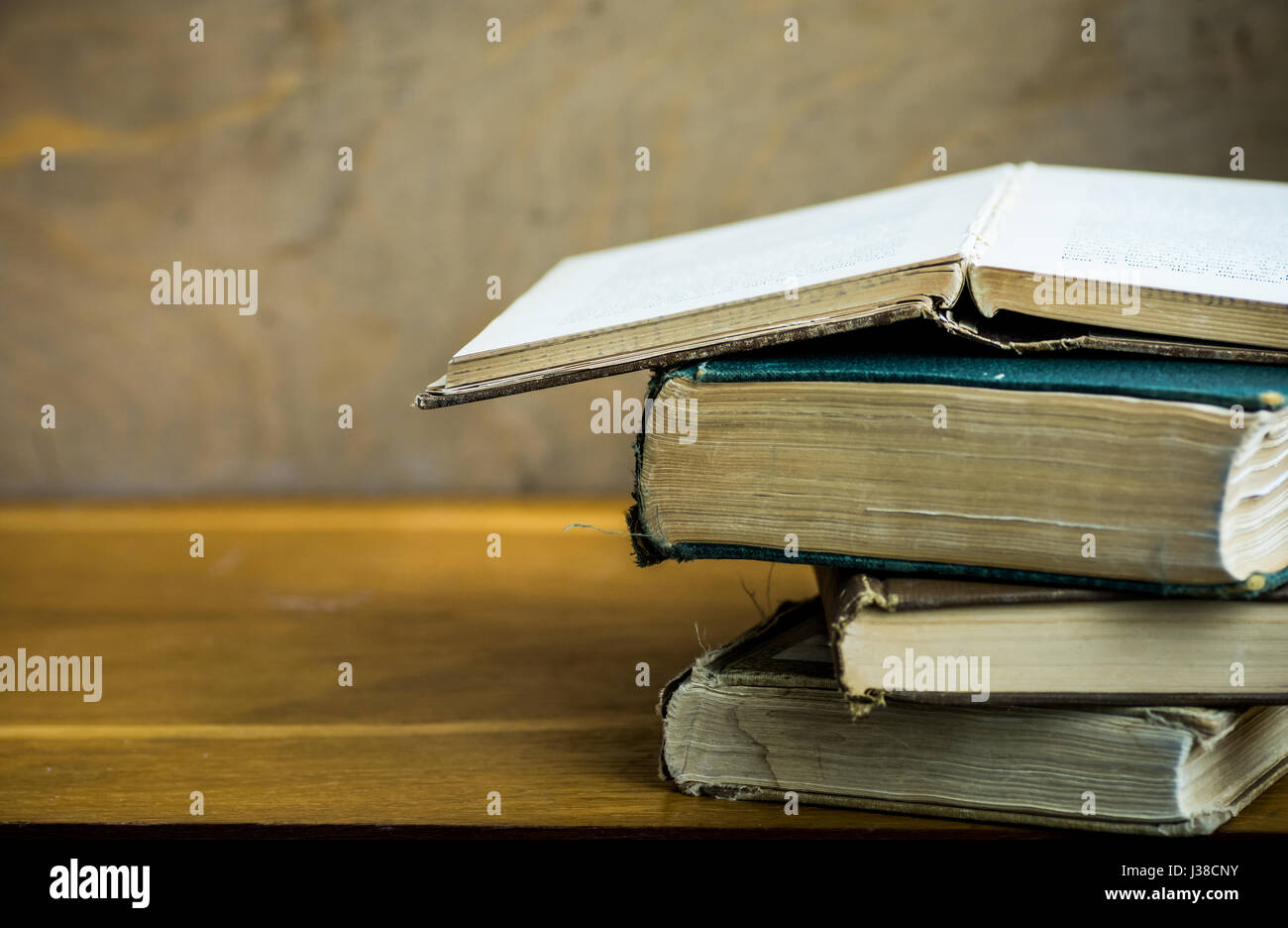 Pile of used old opened books, shabby corners, aged wood desk ...