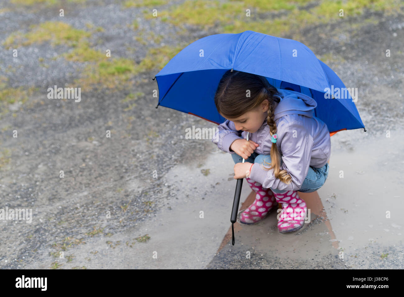 Little girl playing in the rain under umbrella Stock Photo - Alamy