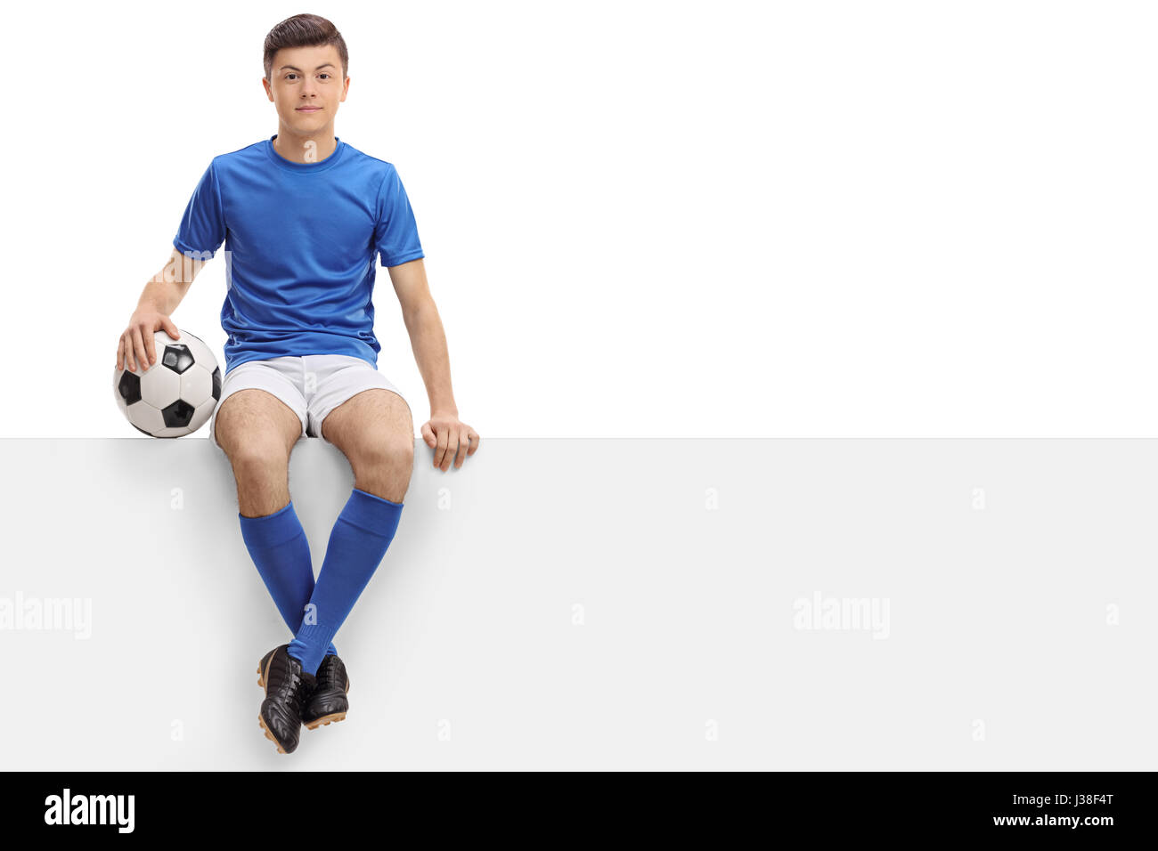Teen football player sitting on a panel and looking at the camera ...