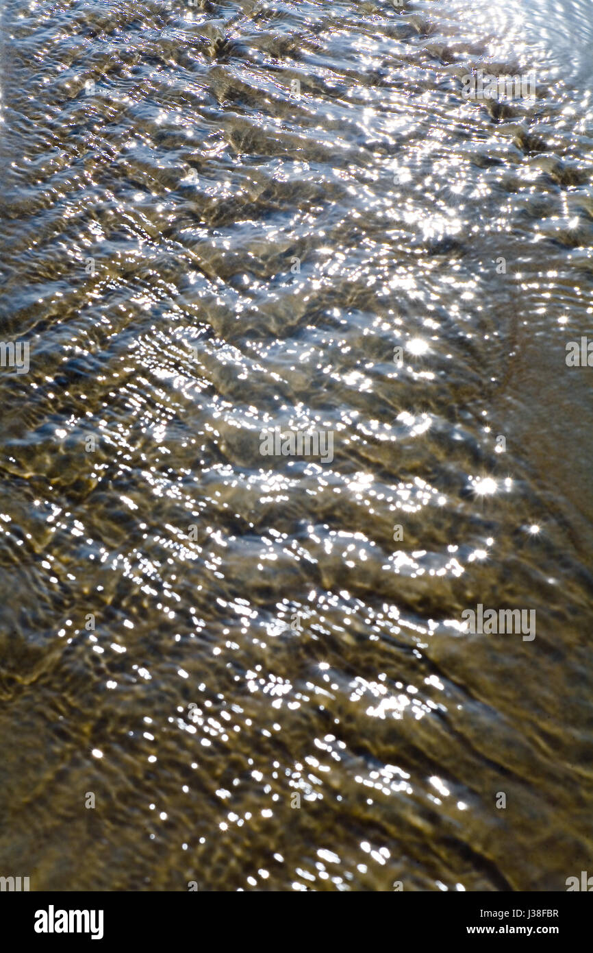 Clean water stream flows through the sand and glare in the sun Stock ...