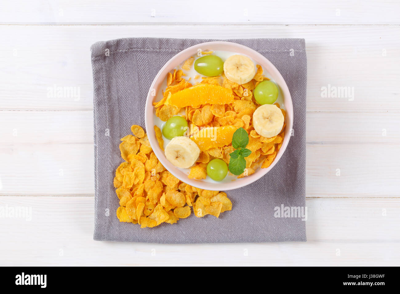 bowl of corn flakes with milk and fresh fruit on grey place mat Stock ...