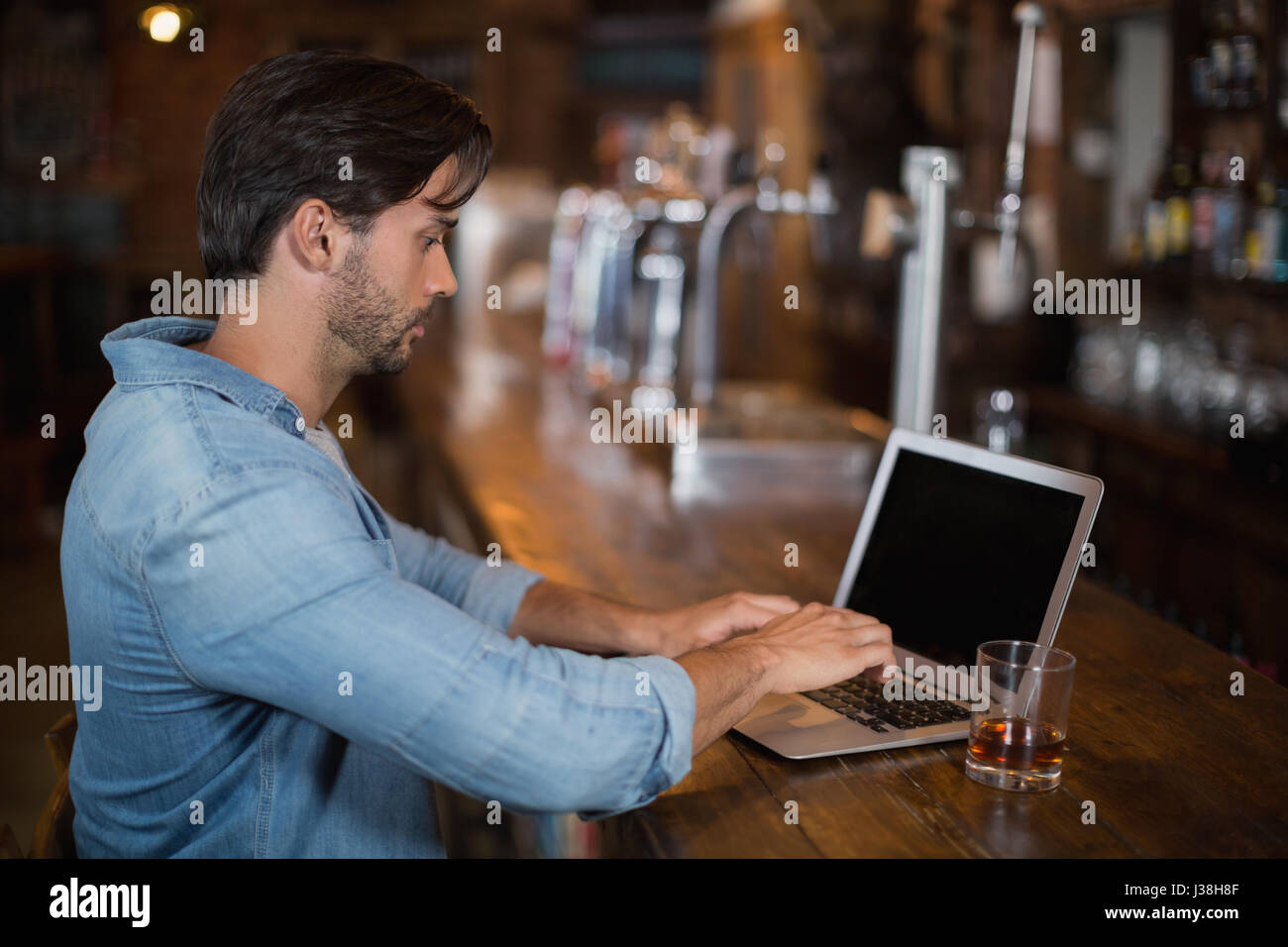 Serious man using laptop at bar counter Stock Photo - Alamy