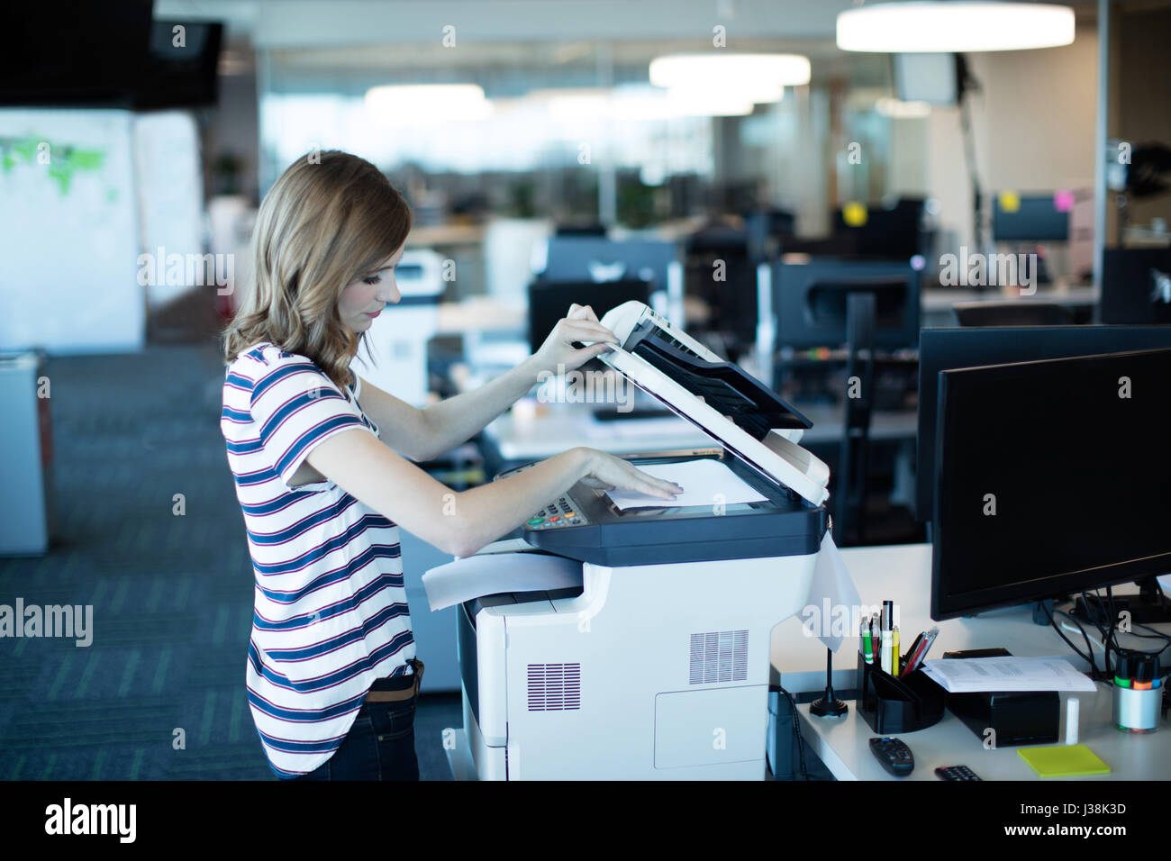Side view of young businesswoman using copy machine in office Stock ...