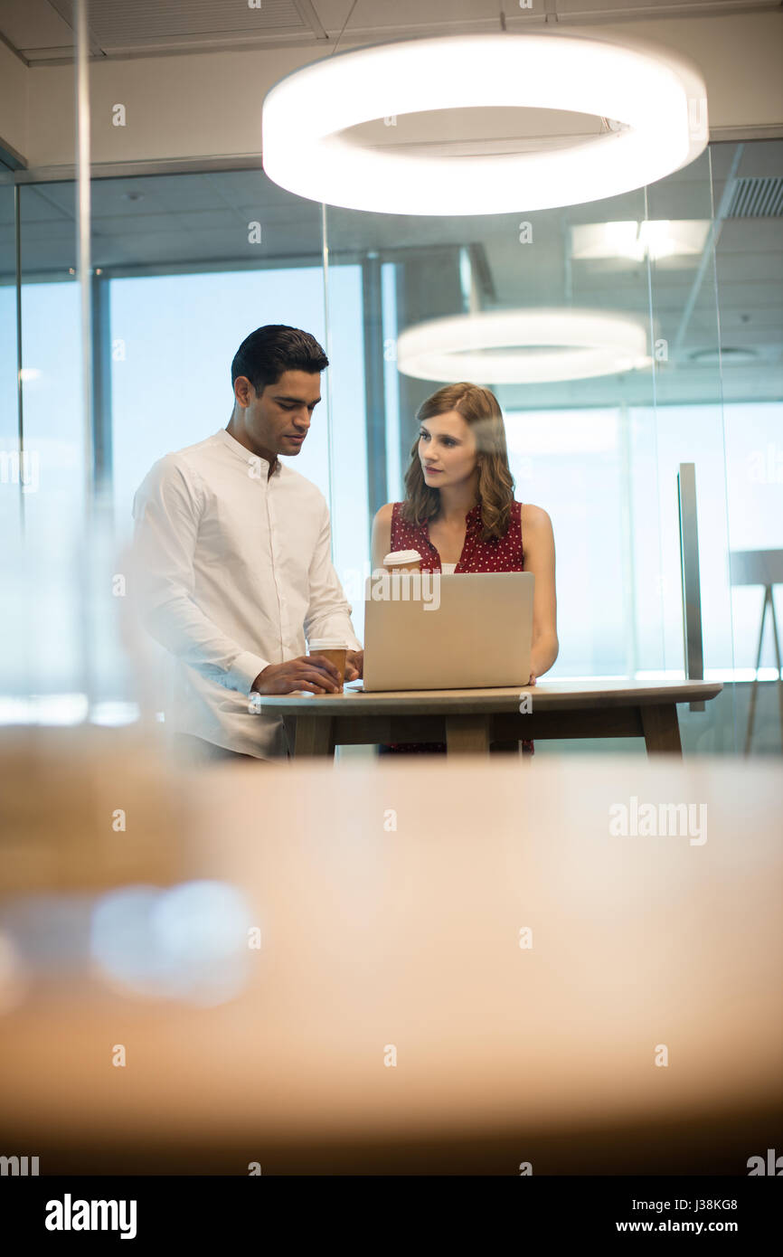 Business people discussing over laptop in illuminated office Stock ...