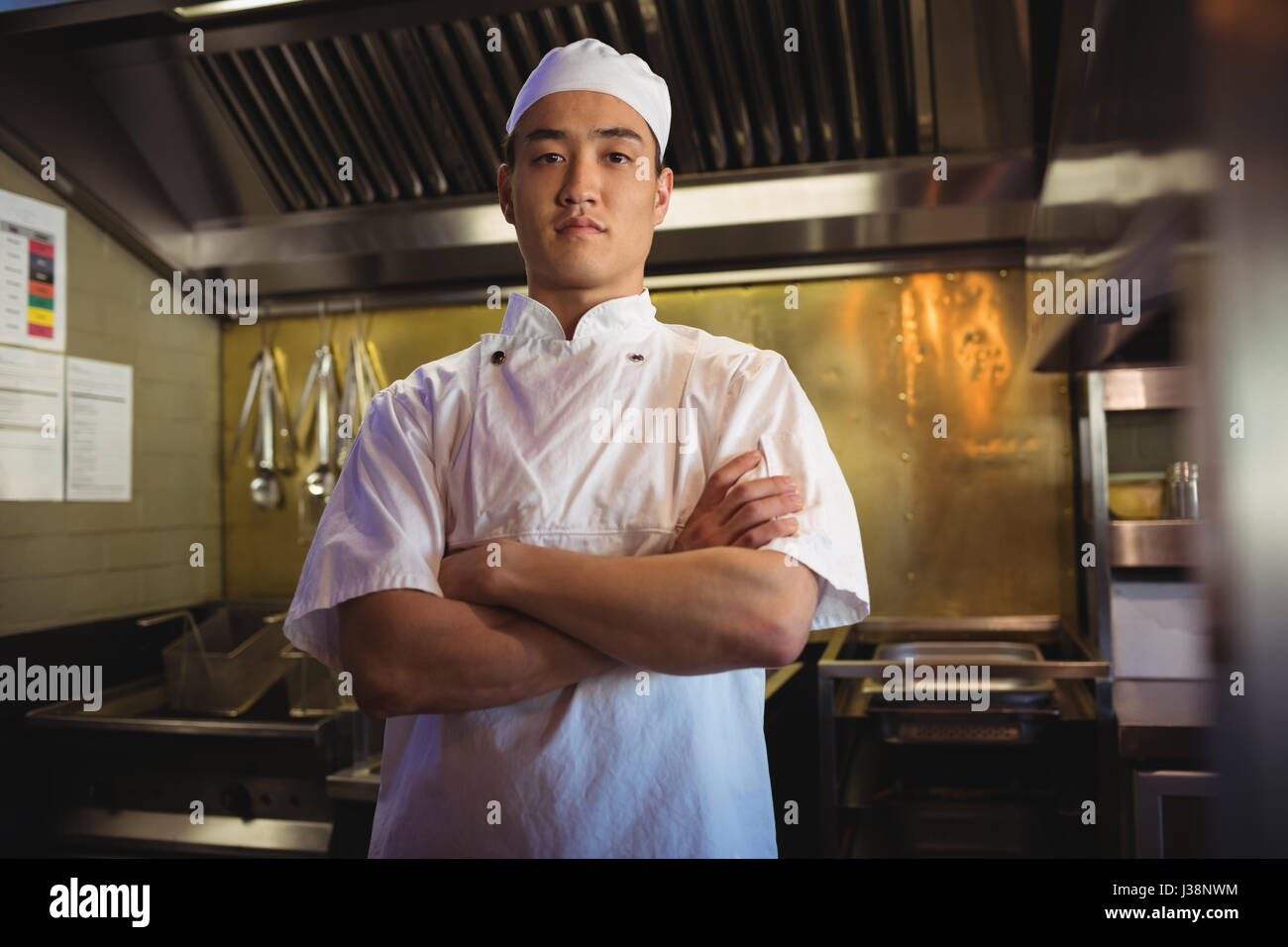 Portrait of chef standing with arms crossed in the commercial kitchen ...