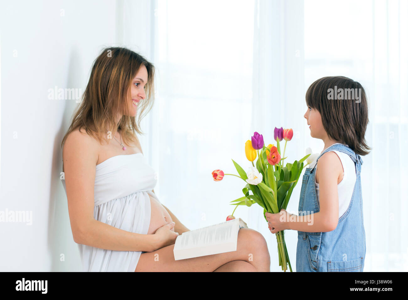 Sweet little preschool child, boy, giving flowers to his pregnant mom ...