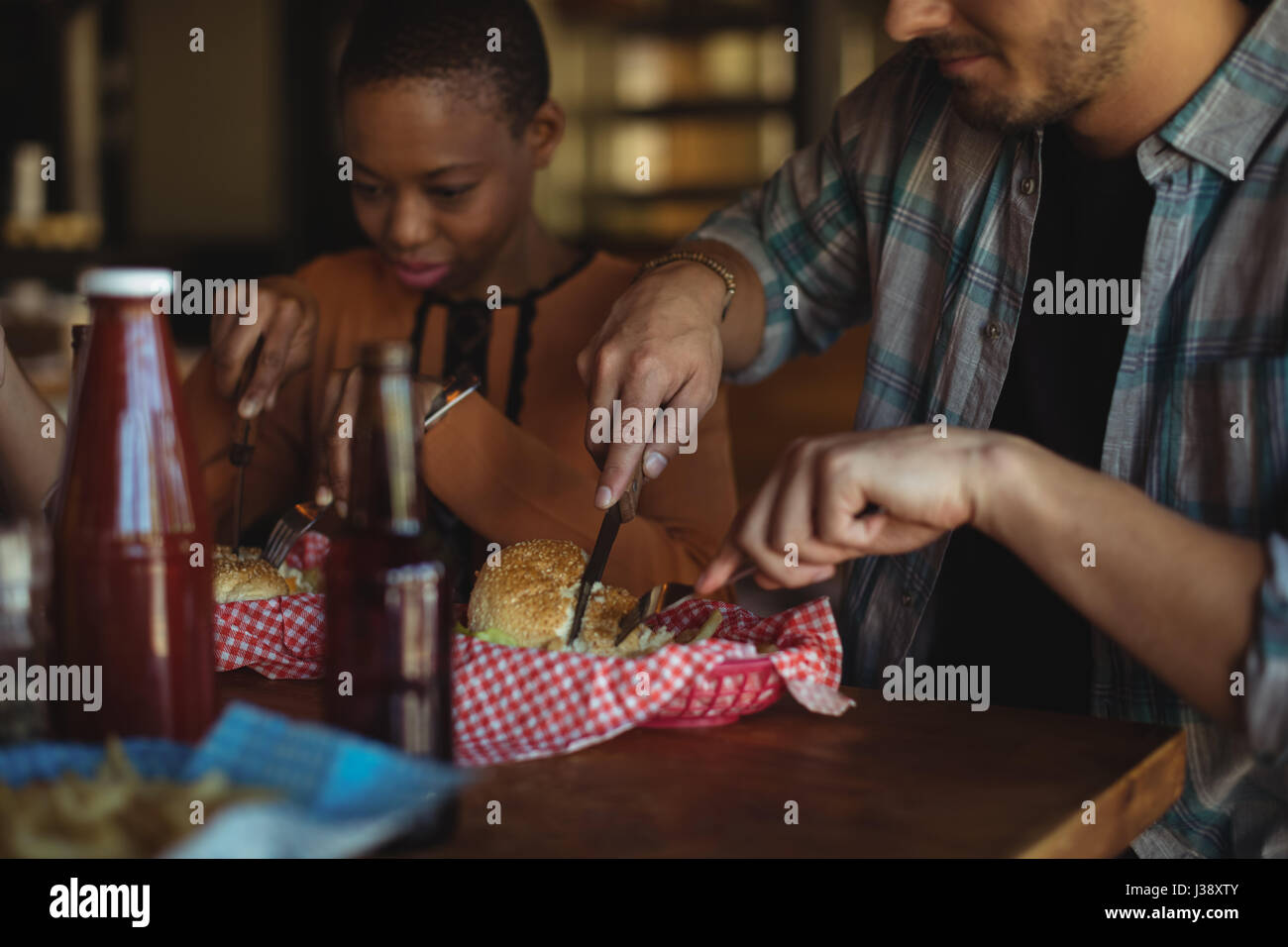 Friends having burger together at restaurant Stock Photo - Alamy