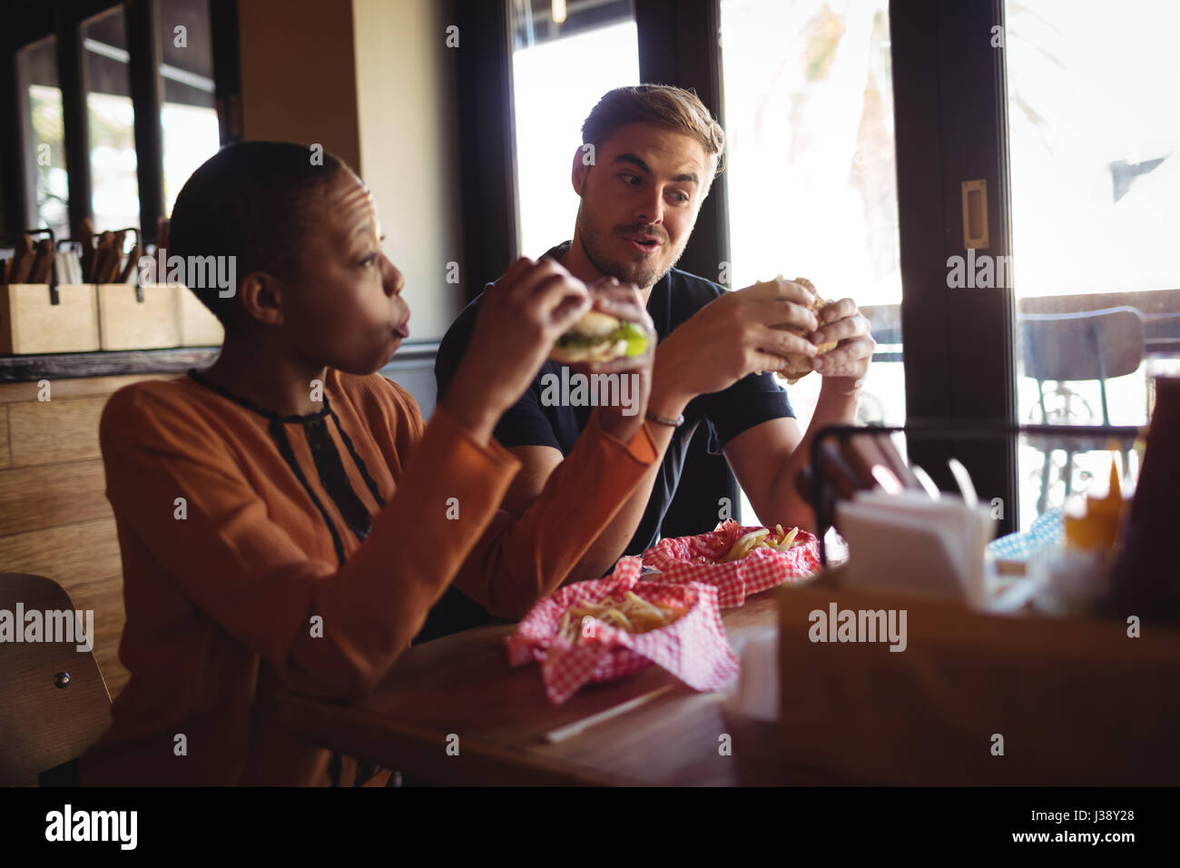 Happy couple eating burger in restaurant Stock Photo - Alamy