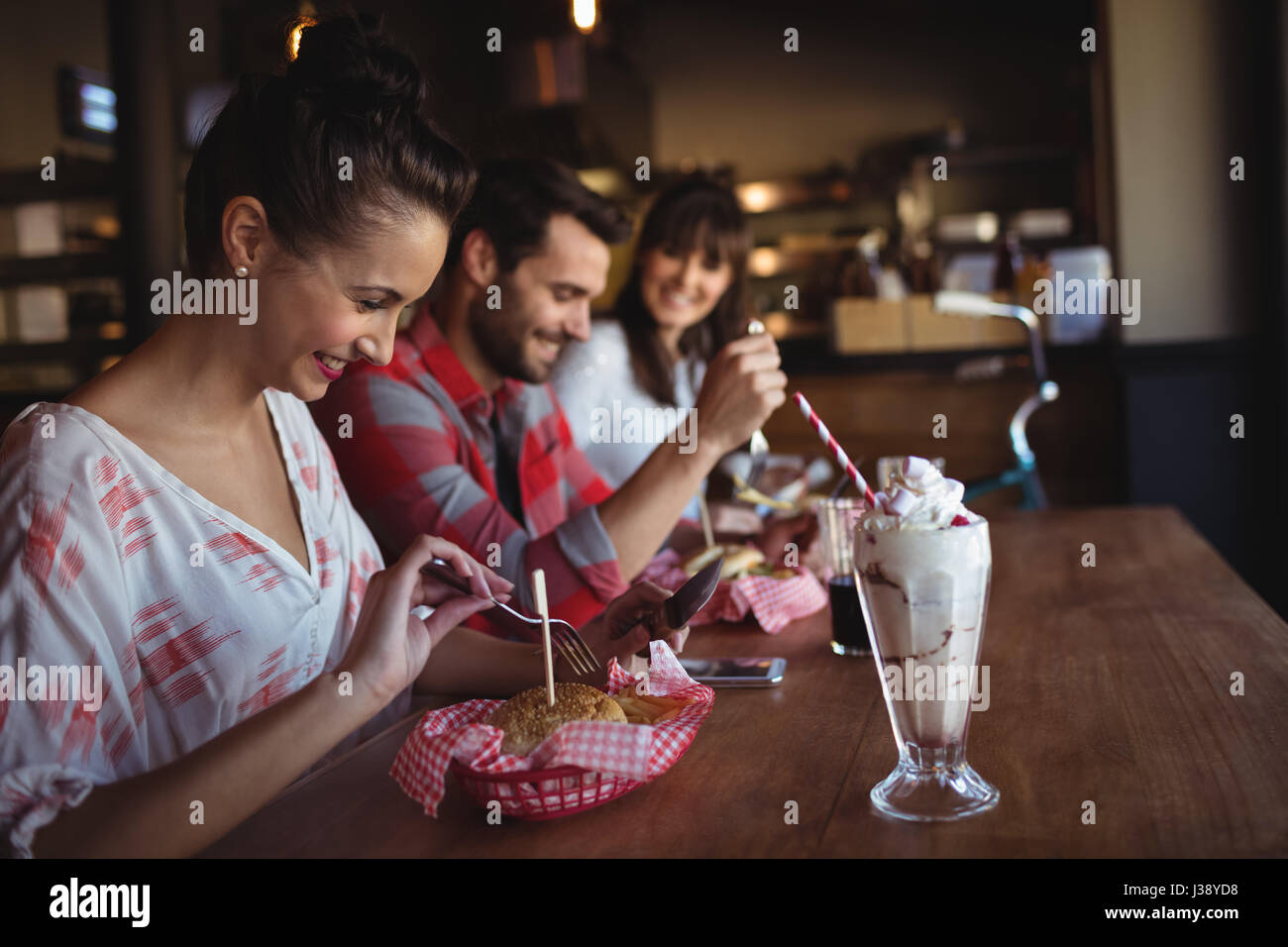 Friends having burger together at restaurant Stock Photo - Alamy