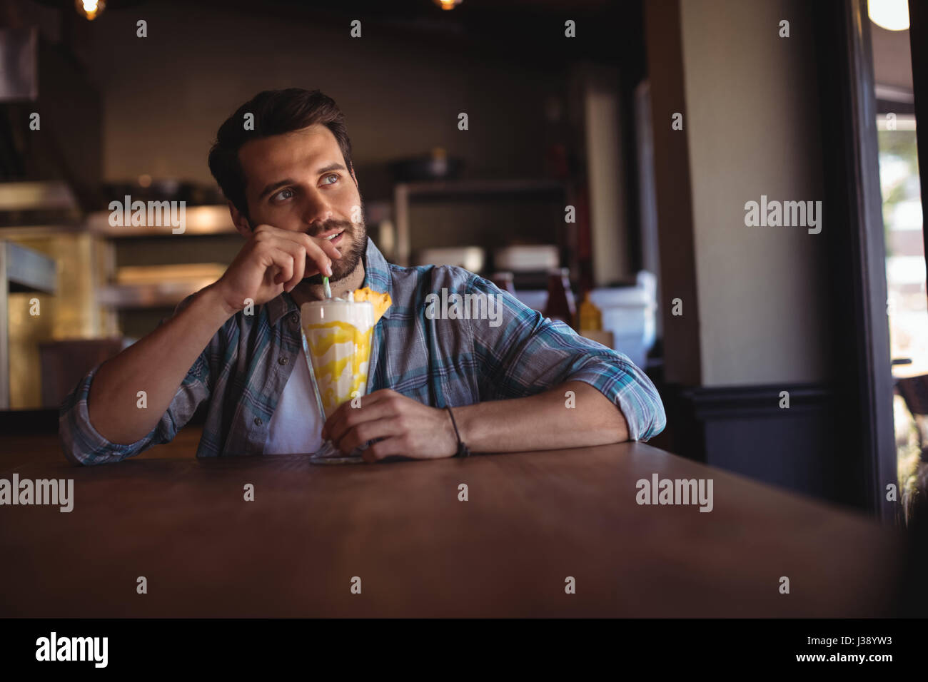 Thoughtful man having milkshake in restaurant Stock Photo - Alamy