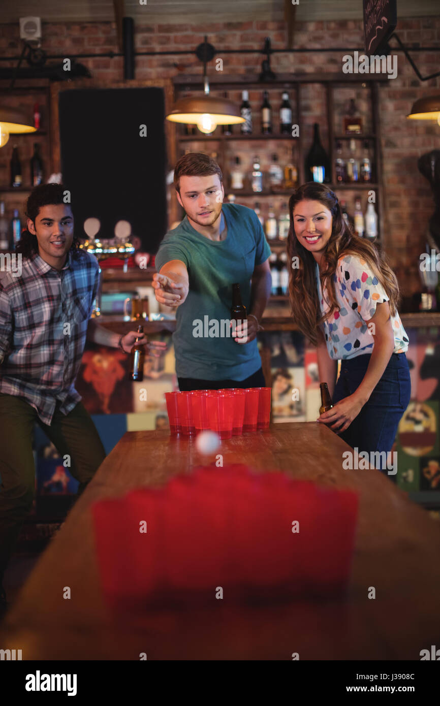 Group of happy friends playing beer pong game in pub Stock Photo - Alamy