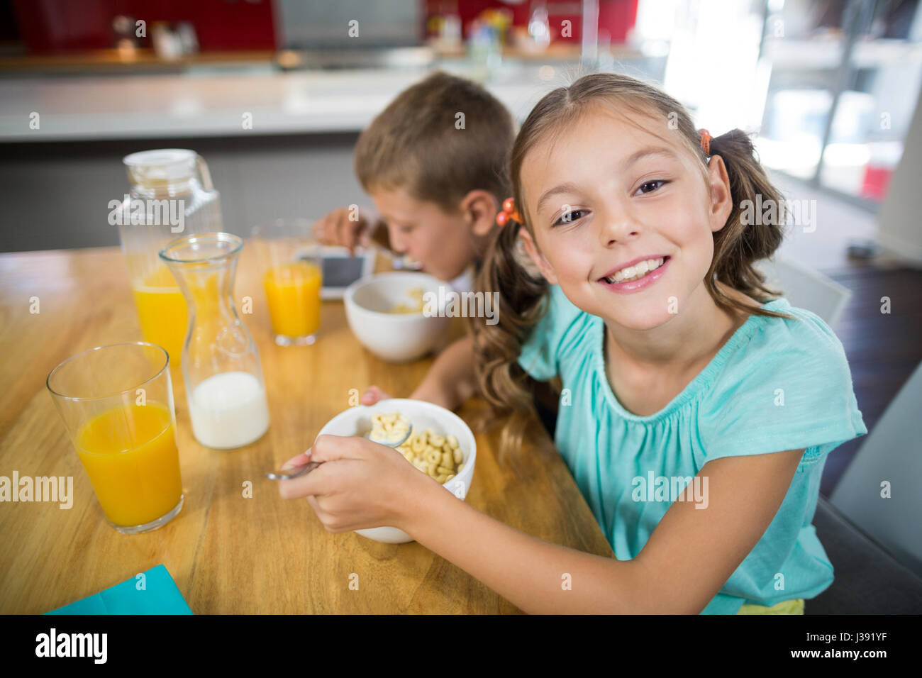 Smiling sibling having breakfast cereal in kitchen at home Stock Photo ...