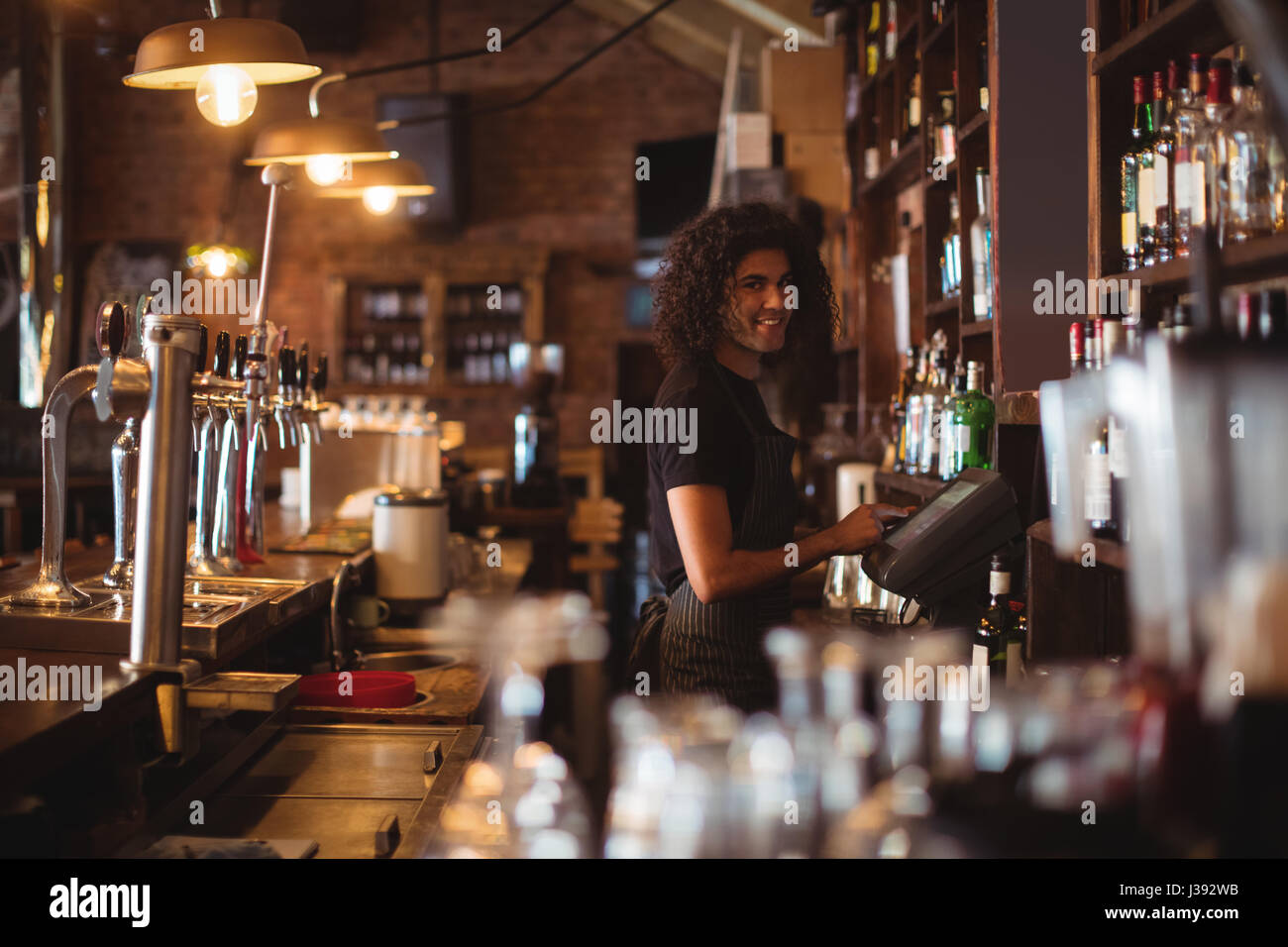 Young waiter using a electronic machine in pub Stock Photo - Alamy