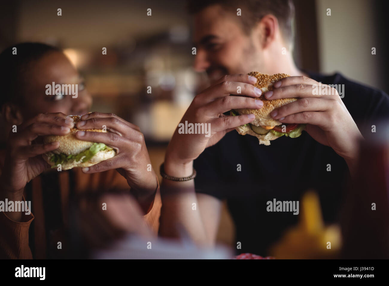 Happy couple having burger in restaurant Stock Photo - Alamy