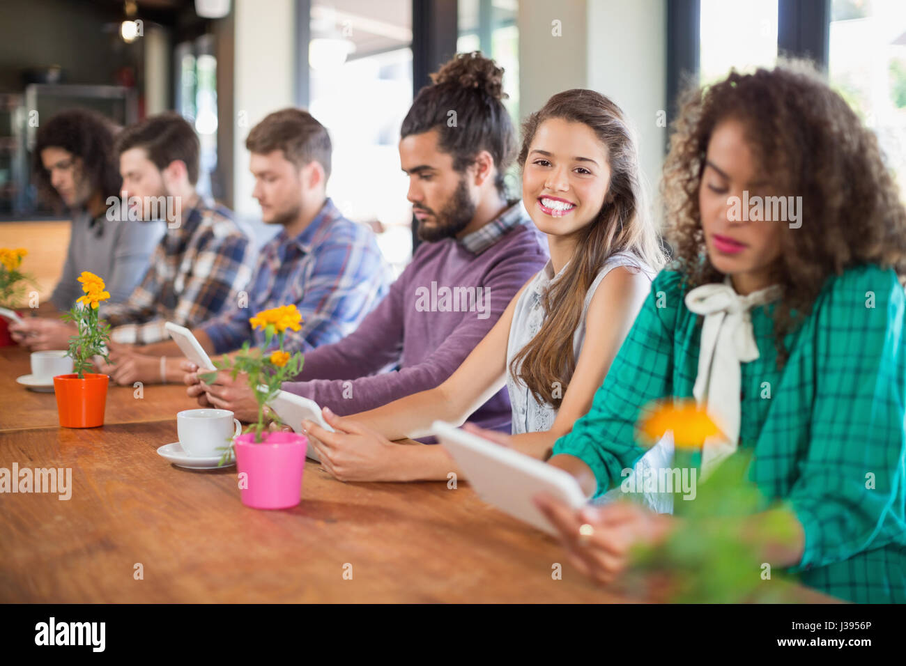 Young people using digital tablets while sitting in restaurant Stock ...
