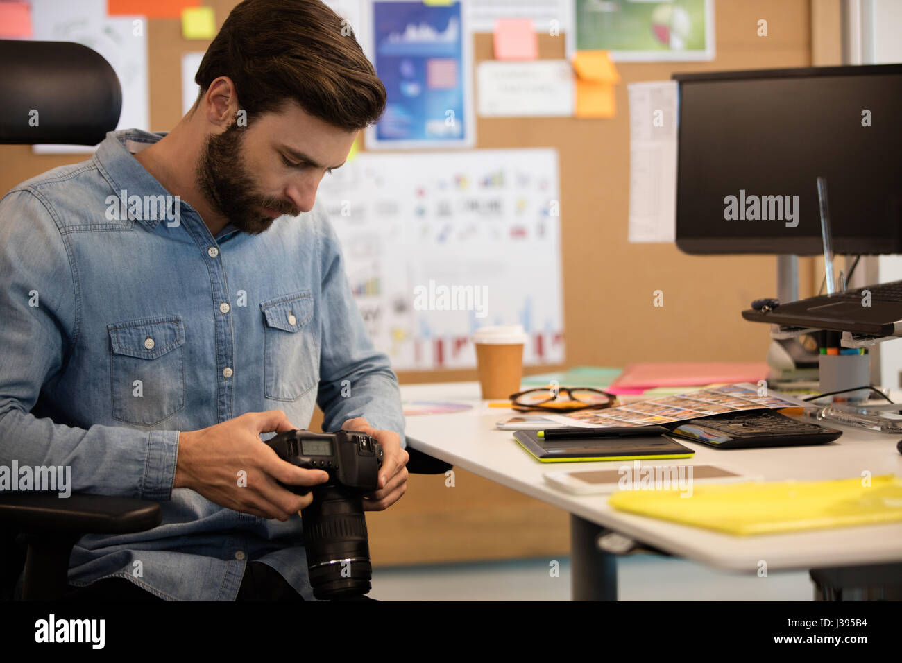 Professional photographer using camera at desk in creative office Stock ...