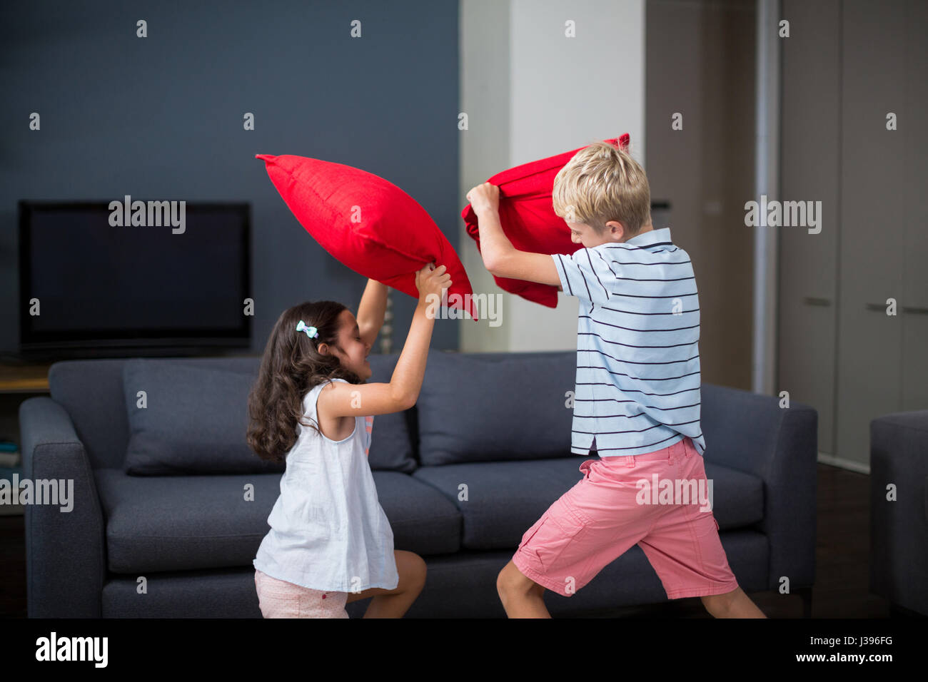 Siblings having pillow fight in living room at home Stock Photo - Alamy