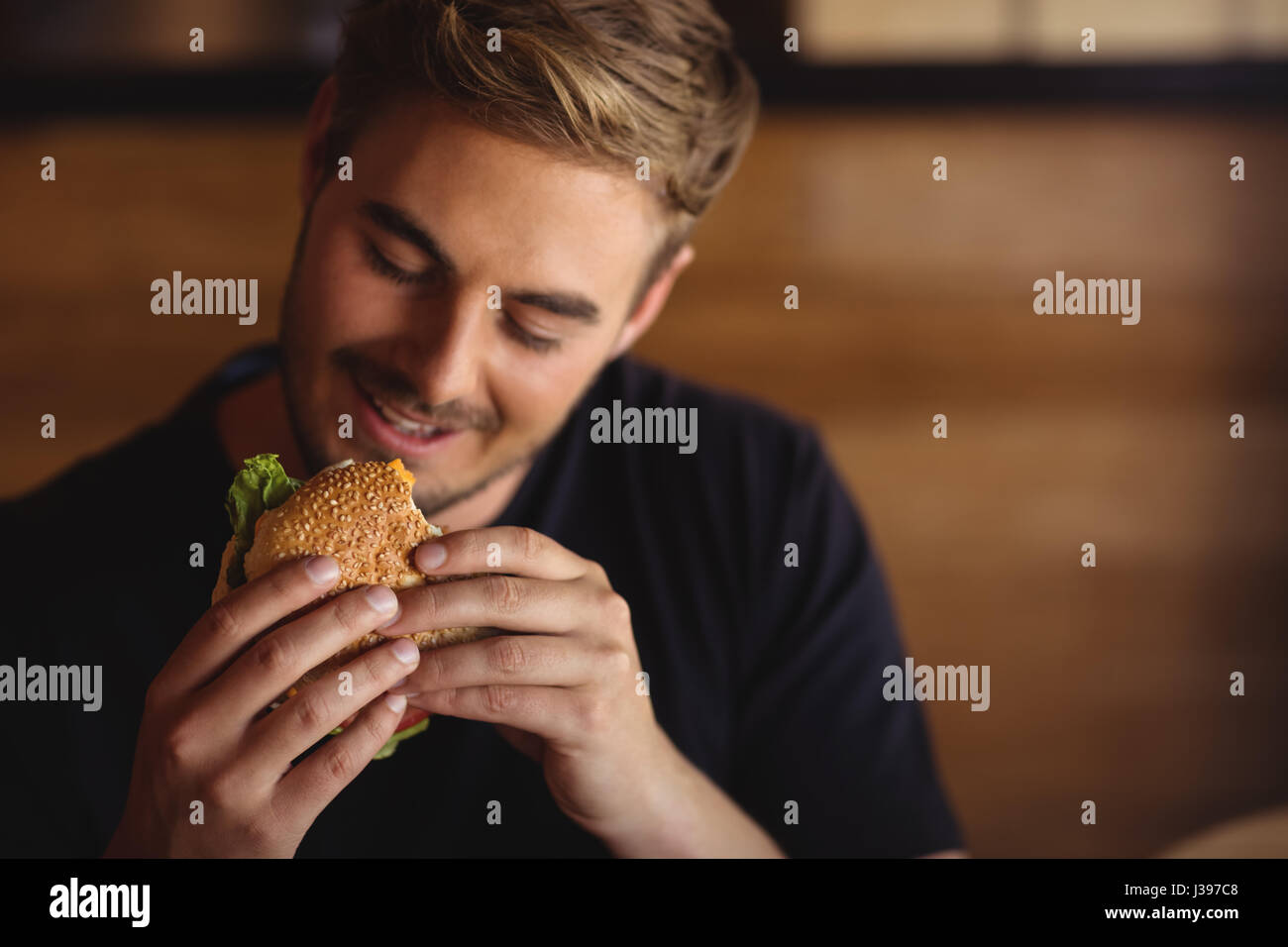 Happy man eating burger in restaurant Stock Photo - Alamy