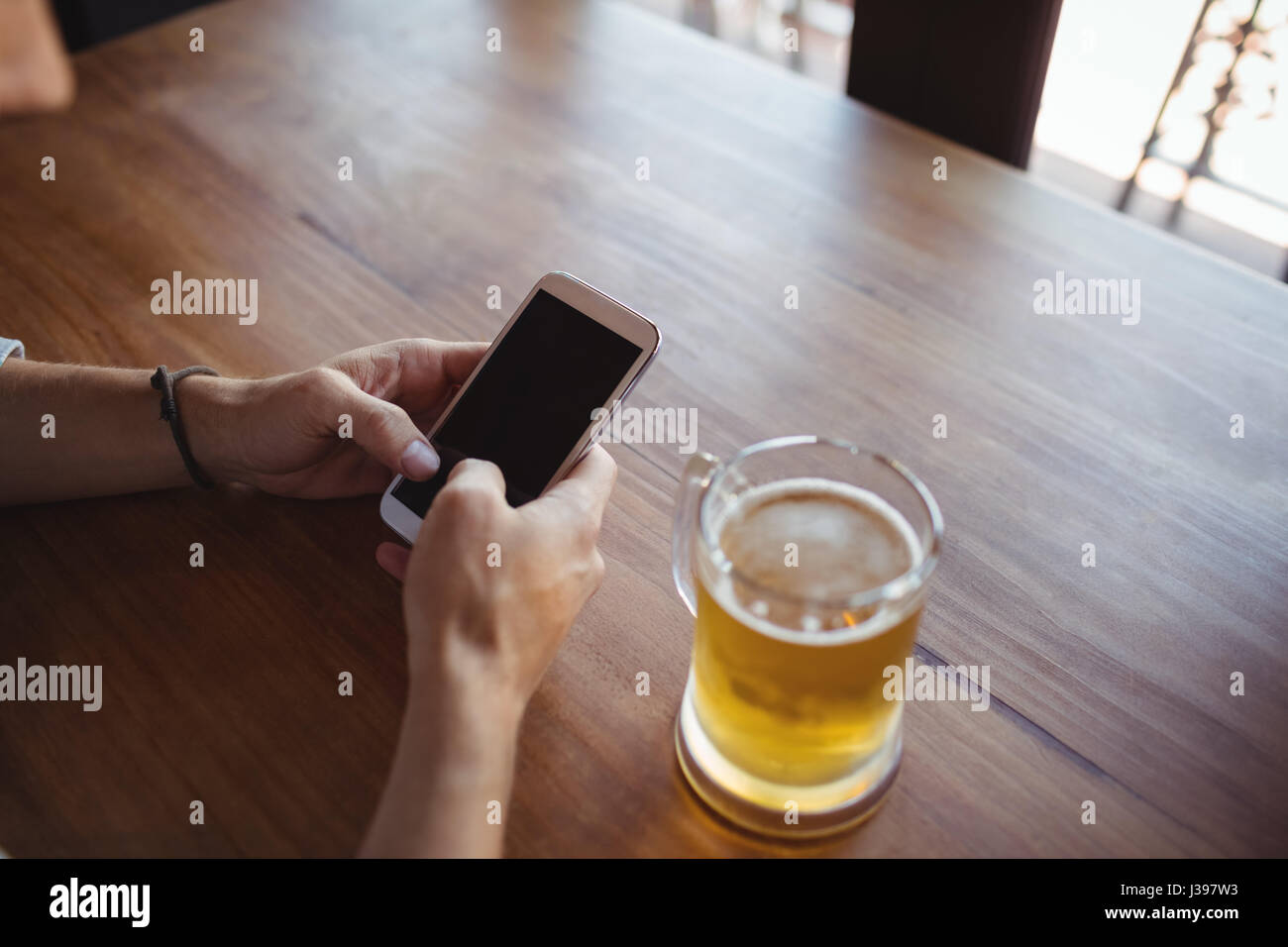 Man using mobile phone while having beer in bar Stock Photo - Alamy