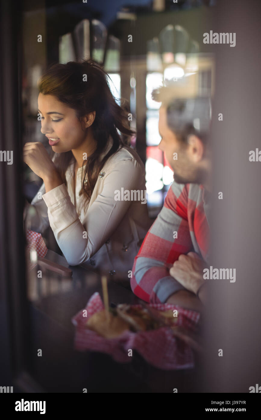 Friends having burger together at restaurant Stock Photo - Alamy