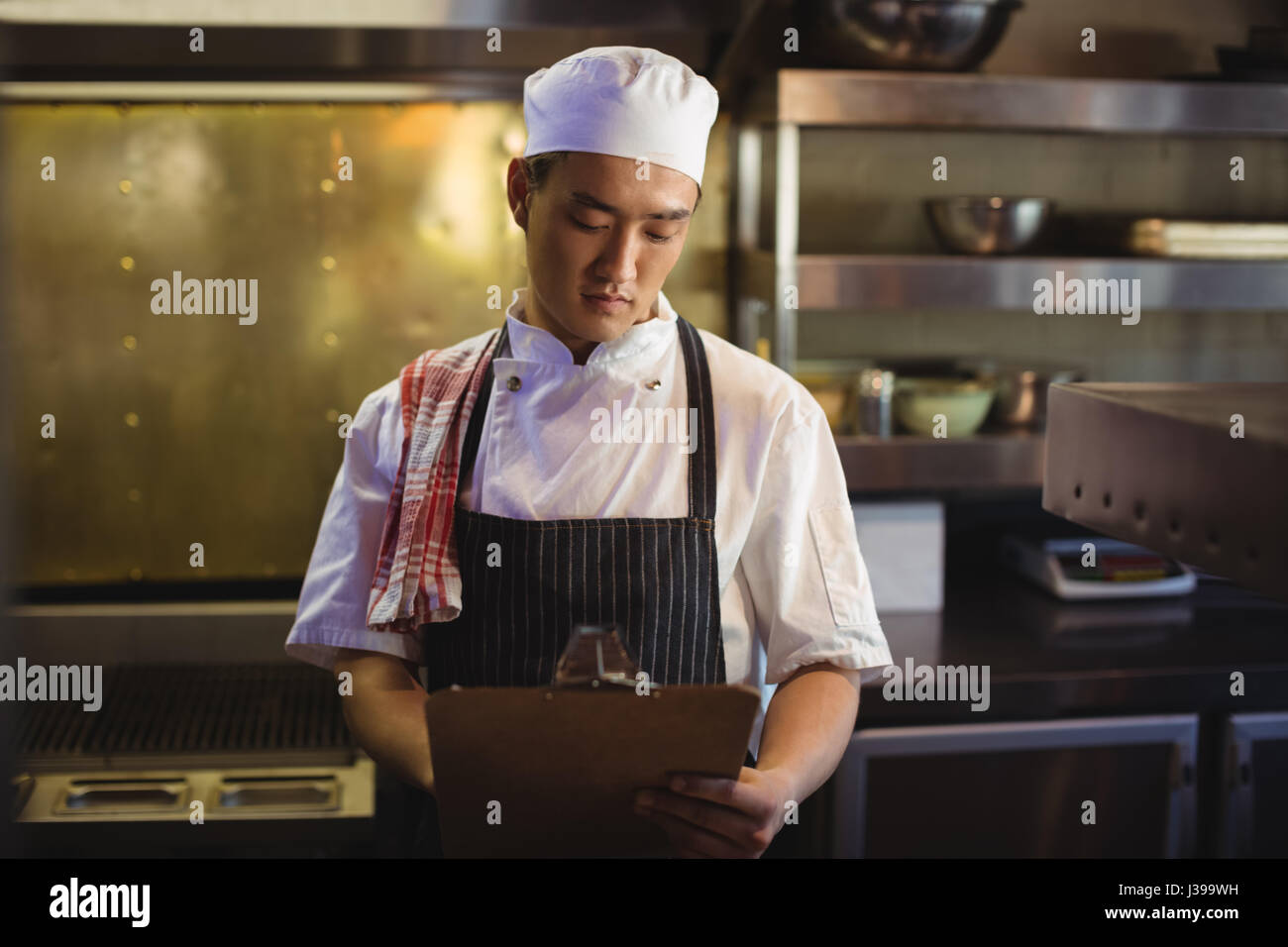 Chef writing on a clipboard in the commercial kitchen Stock Photo - Alamy