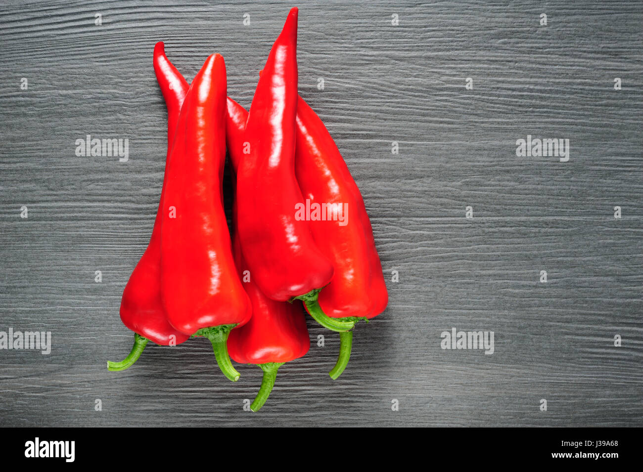 Five ripe sweet red Kapia peppers in heap on dark shale stone ...