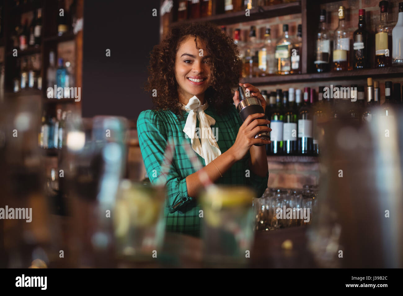 Portrait of female bartender mixing a cocktail drink in cocktail shaker at counter Stock Photo ...