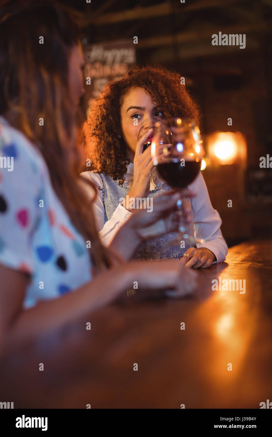 Two beautiful young women having red wine in pub Stock Photo - Alamy