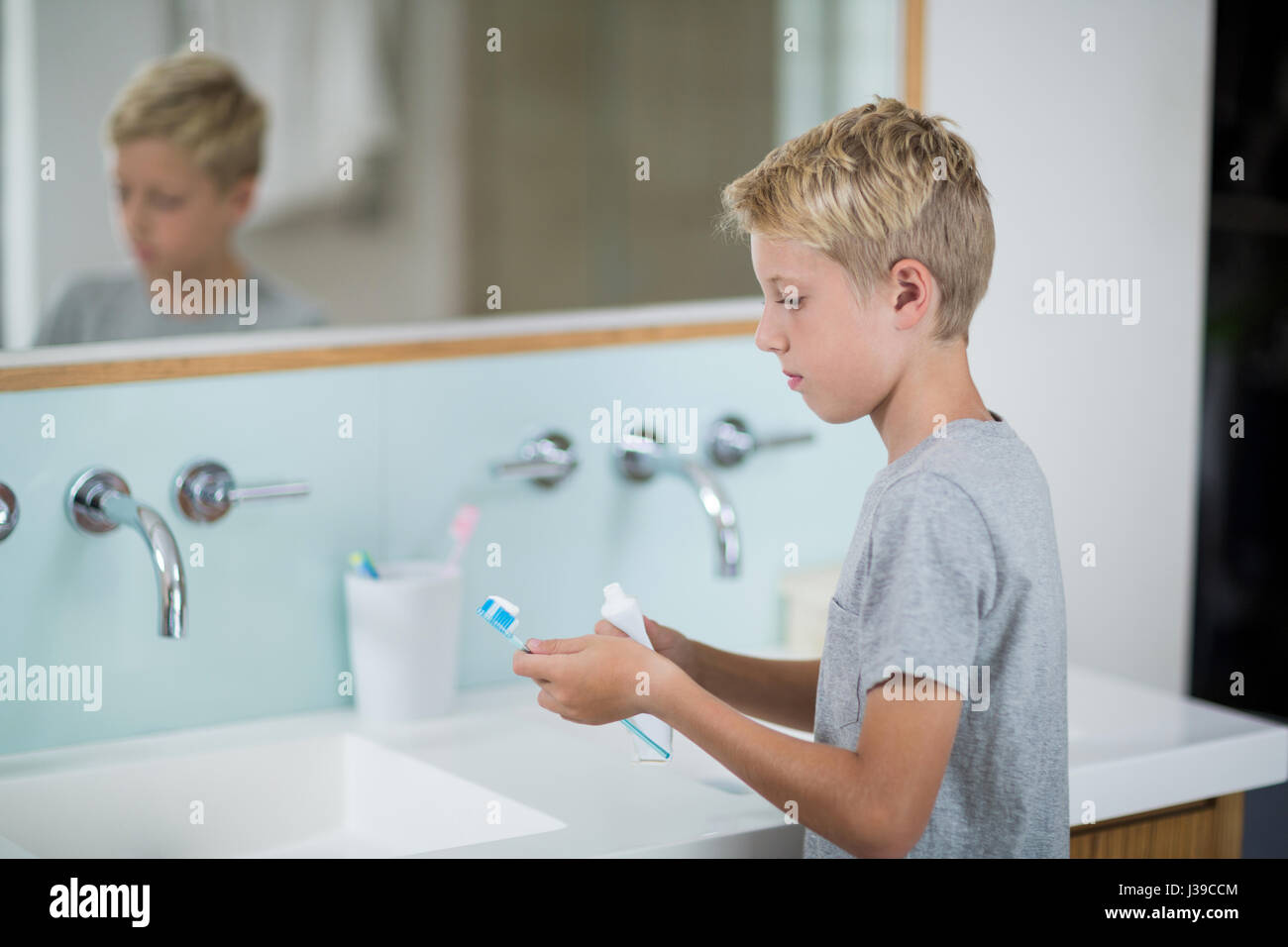 Boy putting toothpaste on brush in bathroom at home Stock Photo - Alamy