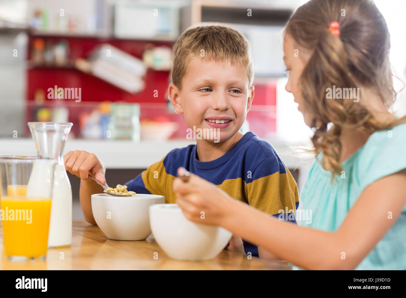 Smiling sibling having breakfast cereal in kitchen at home Stock Photo ...