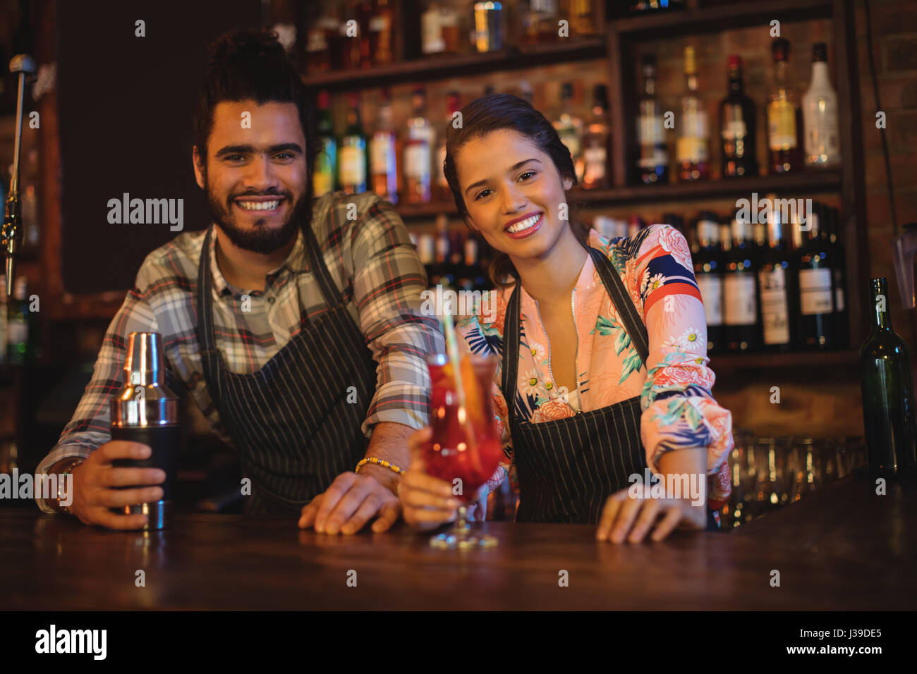 Portrait of happy waiter and waitress standing at counter in pub Stock ...
