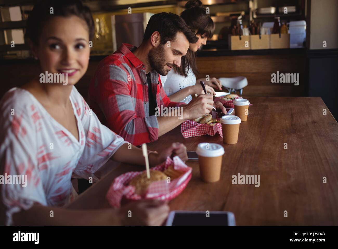 Friends having burger together at restaurant Stock Photo - Alamy